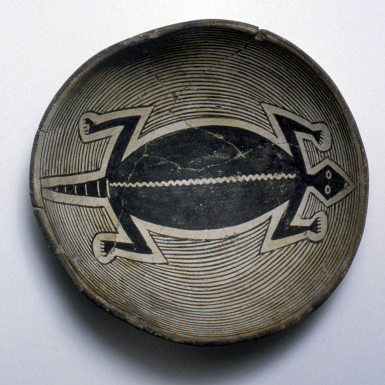 Mimbres pot, black on white, with a stylized lizard. The circular lines ...
